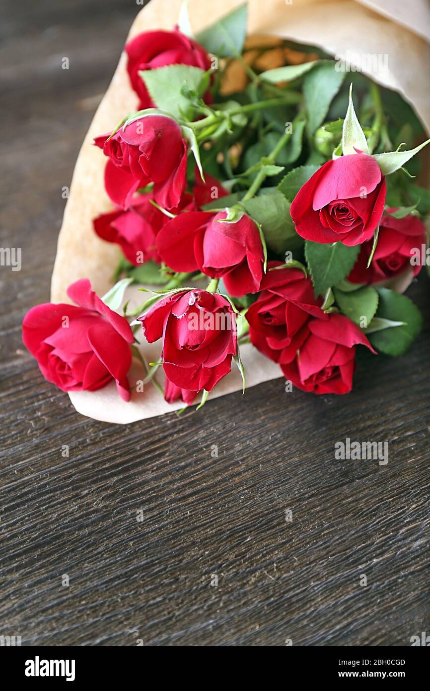 Red roses wrapped in paper on wooden table background Stock Photo - Alamy