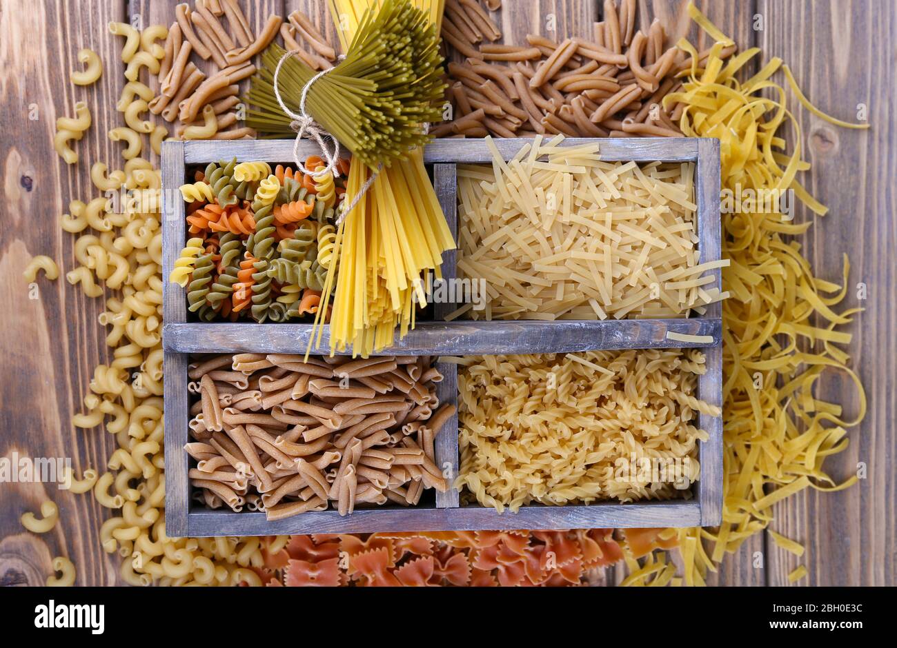 Different types of pasta in box on wooden background Stock Photo - Alamy
