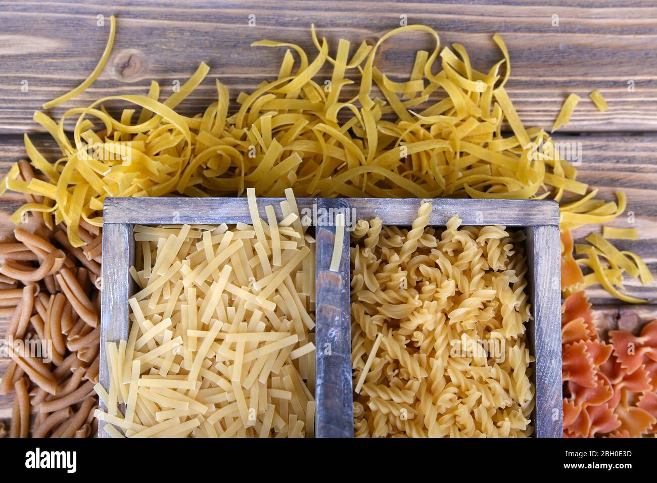 Different types of pasta in box on wooden background Stock Photo - Alamy