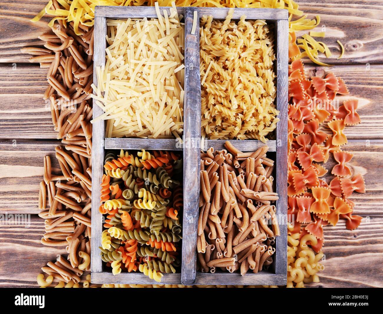 Different types of pasta in box on wooden background Stock Photo - Alamy