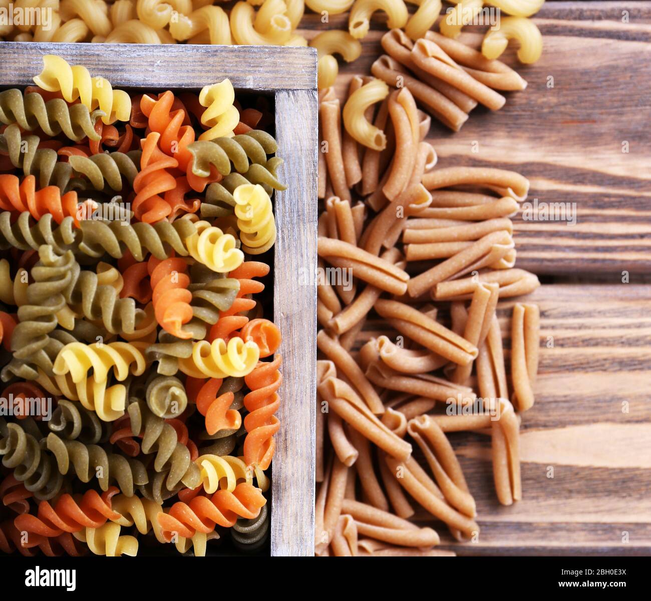Different types of pasta in box on wooden background Stock Photo - Alamy