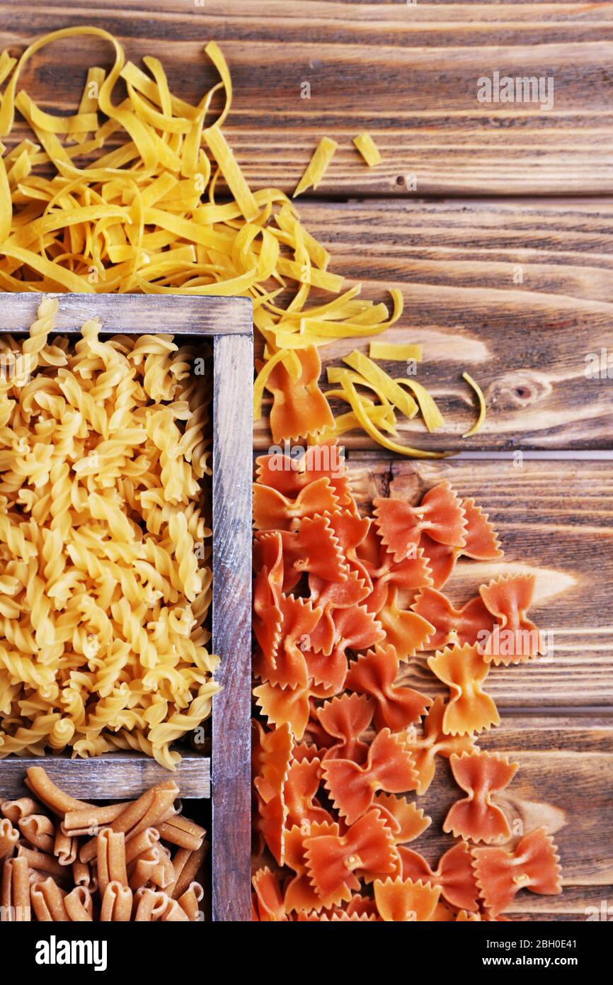 Different types of pasta in box on wooden background Stock Photo - Alamy