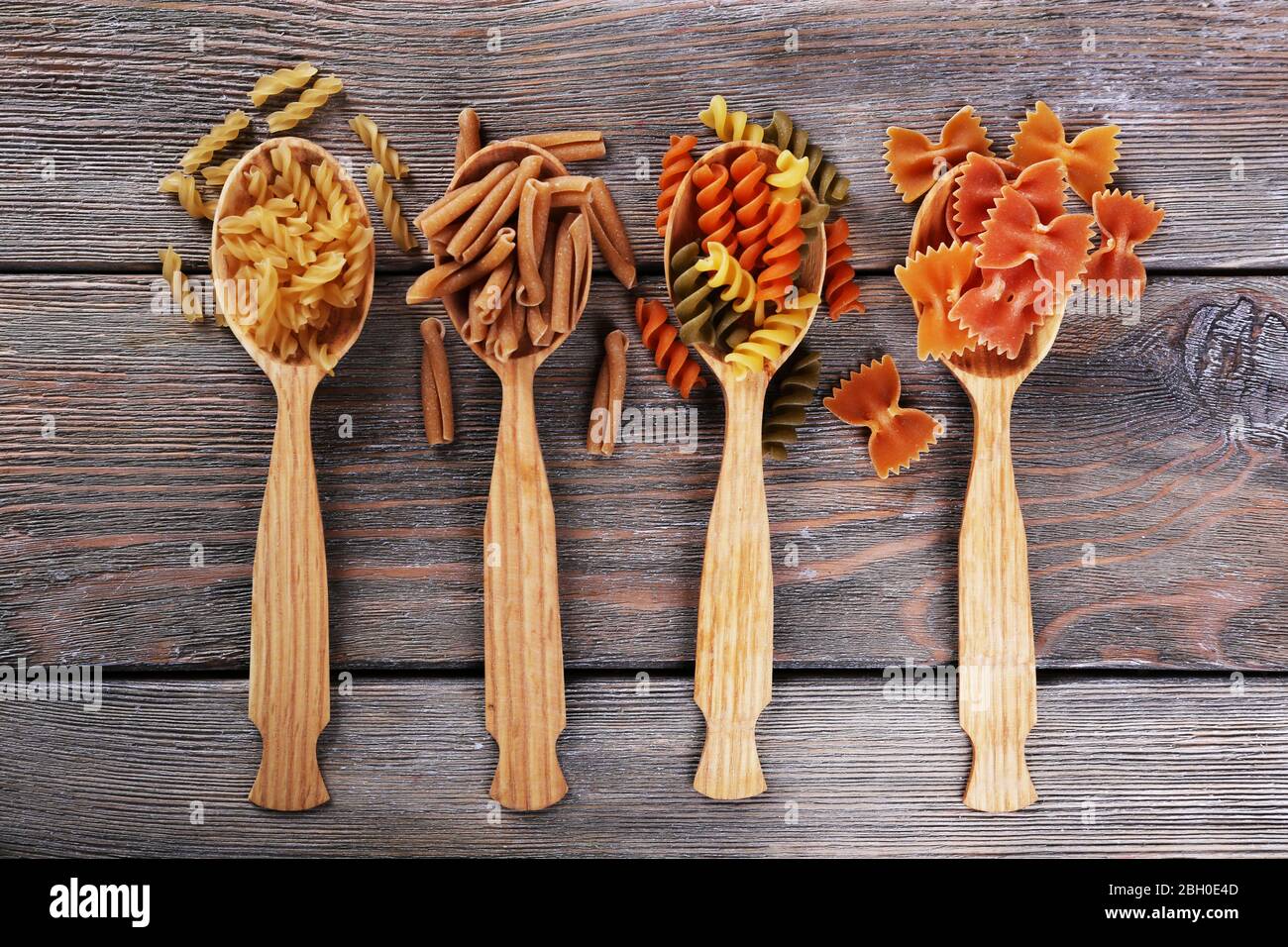 Different types of pasta in spoons on wooden background Stock Photo - Alamy