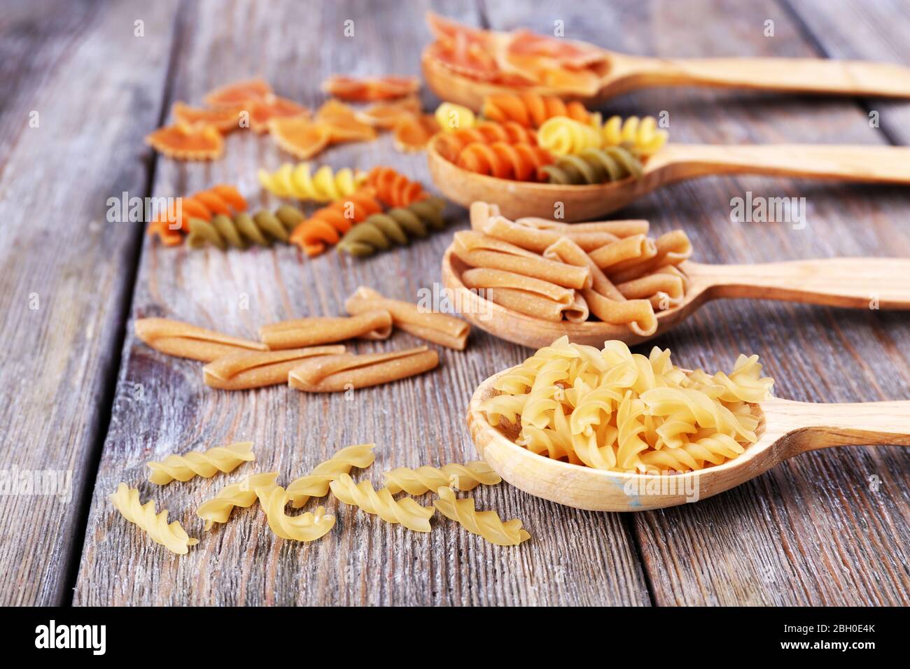 Different types of pasta in spoons on wooden background Stock Photo - Alamy