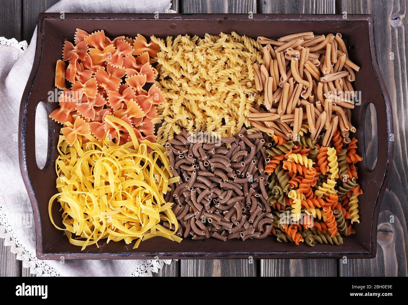 Different types of pasta in tray on wooden background Stock Photo - Alamy