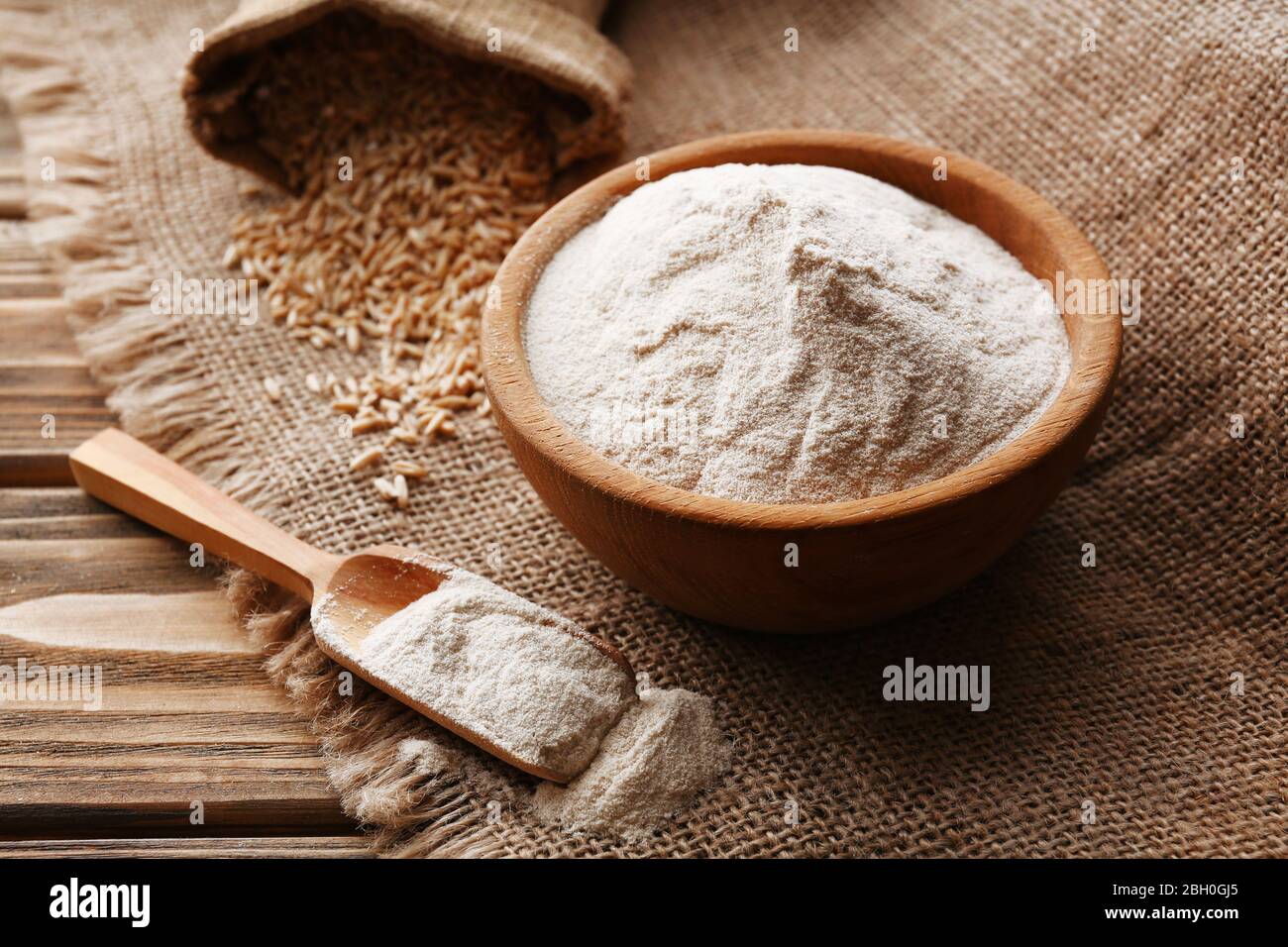 Flour in bowl with grains in bag on sackcloth background Stock Photo ...