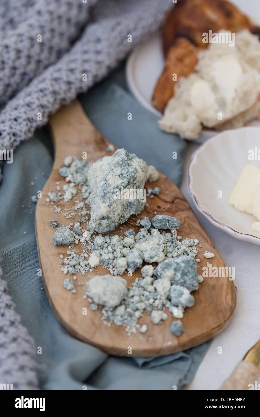 Vertical image of blue lamb cheese placed on a wooden olive board ...