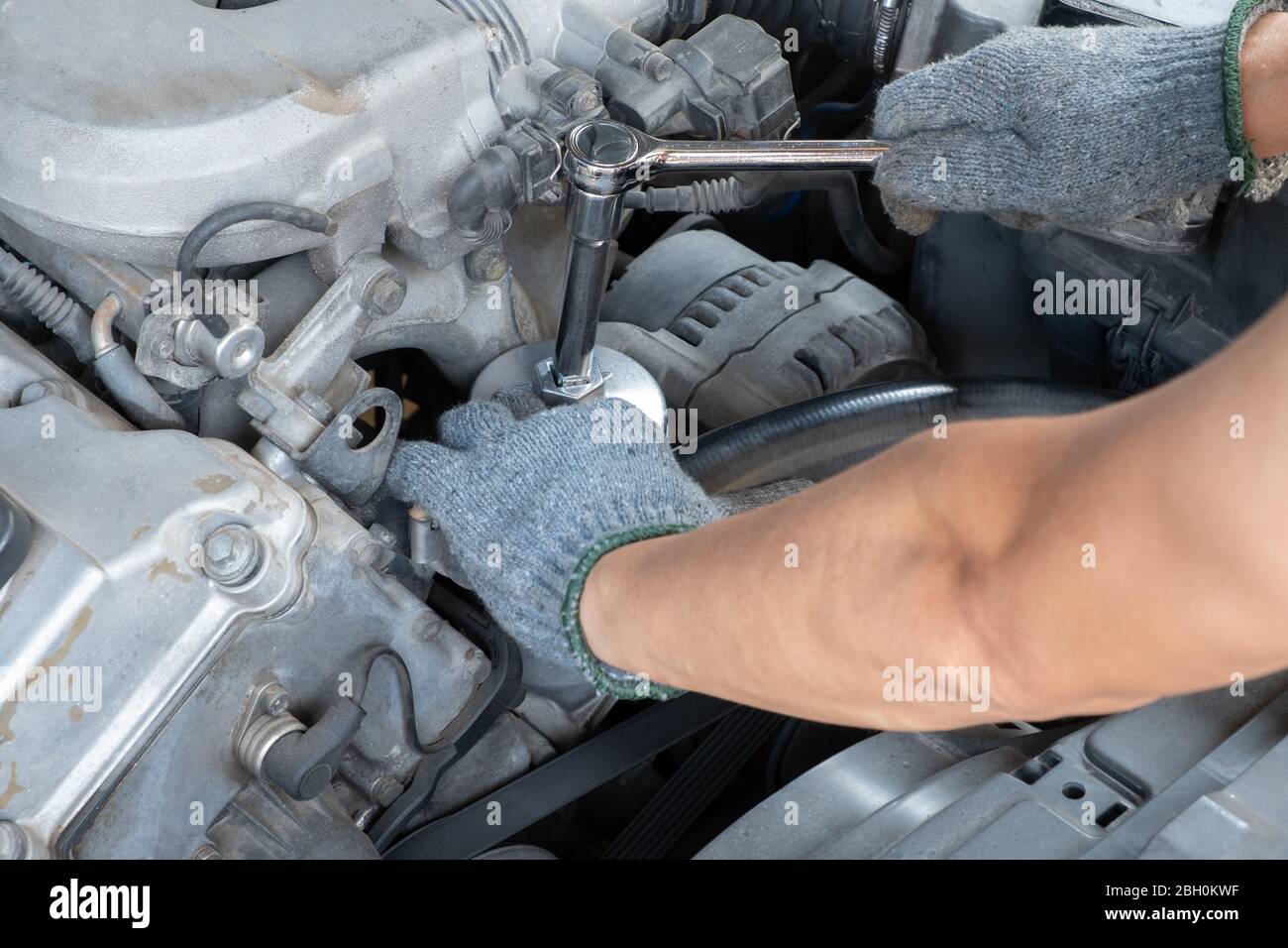 The car mechanic is exerting a long handle torque wrench with a glove ...