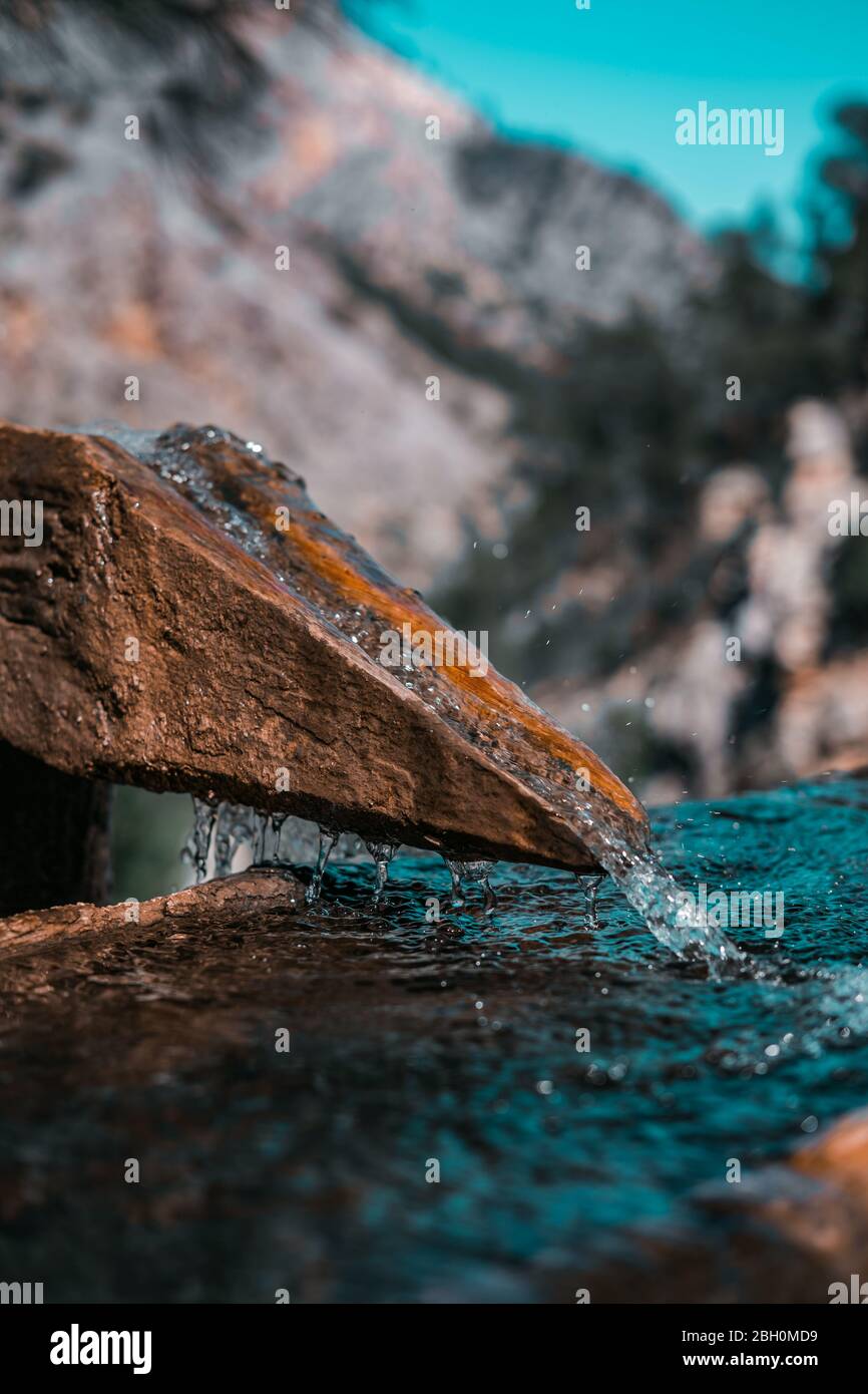 Close image of a spring water pouring down from small stone channel ...