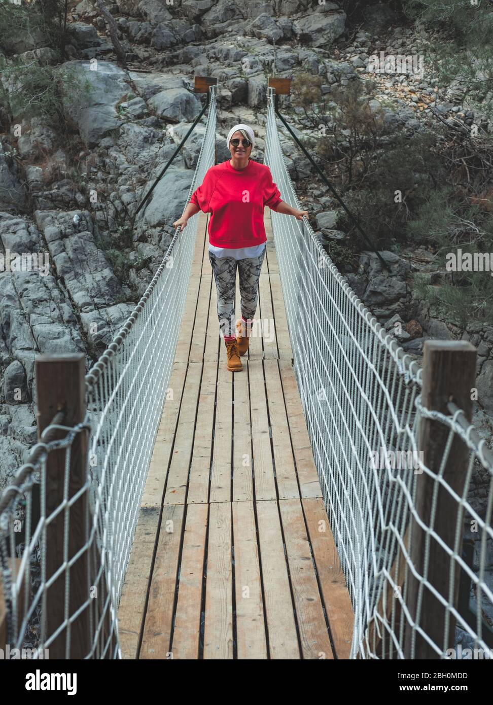 Adult woman standing on a hanging wooden bridge in the nature. Female ...