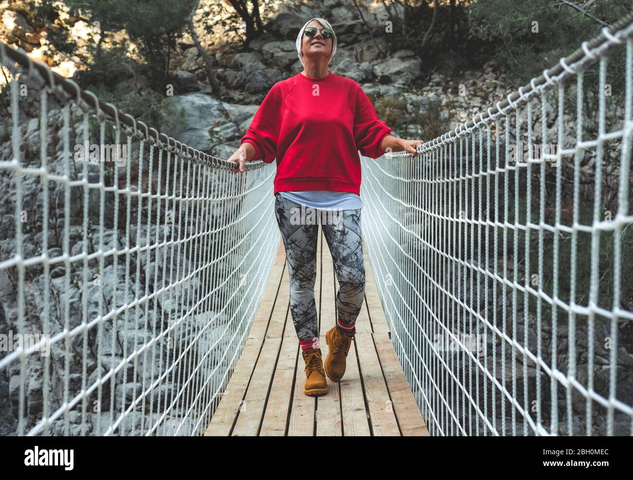 Adult woman standing on a hanging wooden bridge in the nature. Female ...