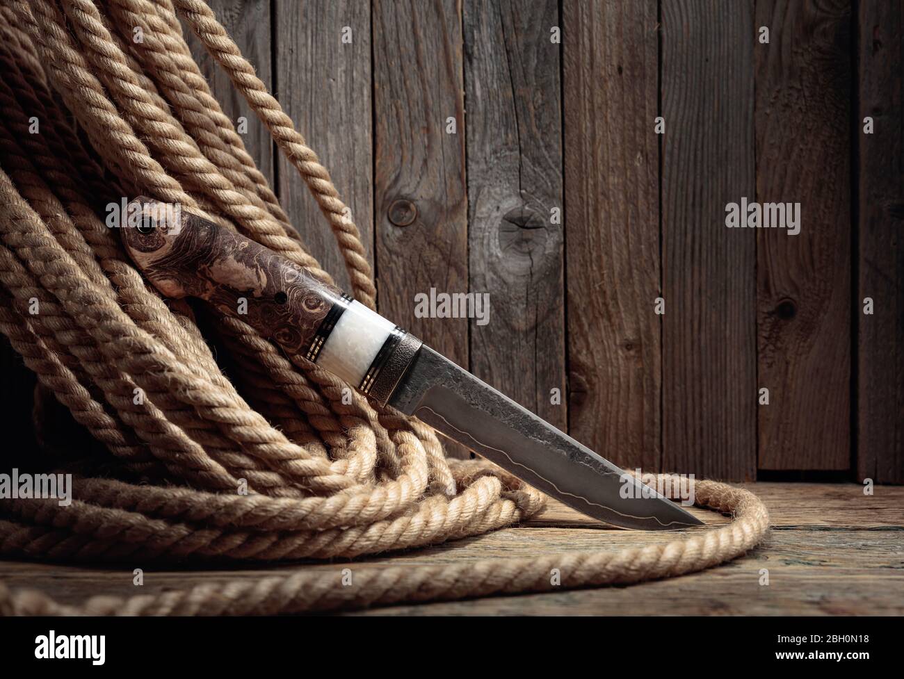 Hunter combat hand made knife and hemp rope on wooden background. The ...