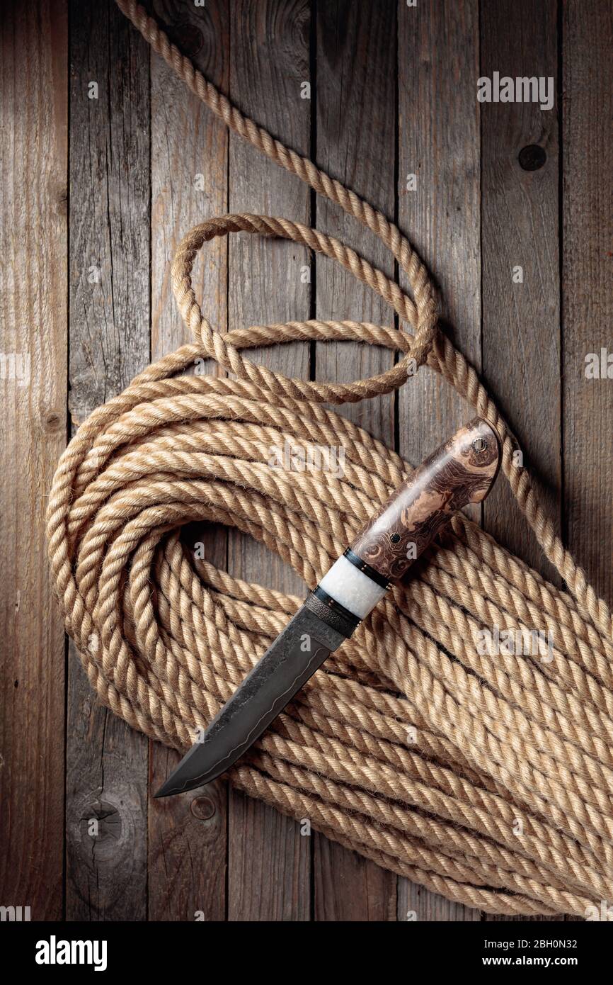 Hunter combat hand made knife and hemp rope on wooden background. The ...