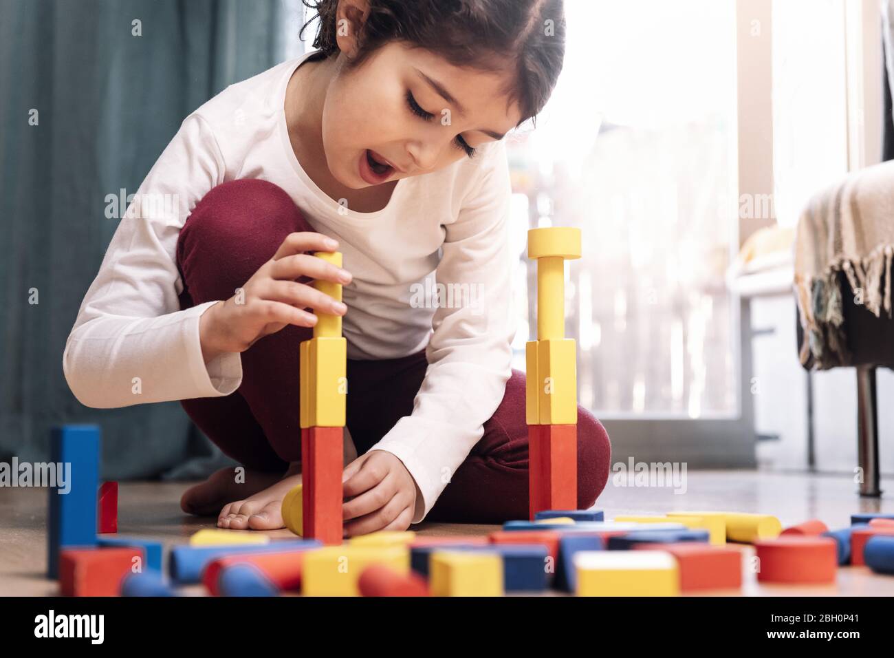 little girl playing at home with building blocks, concept of indoor ...