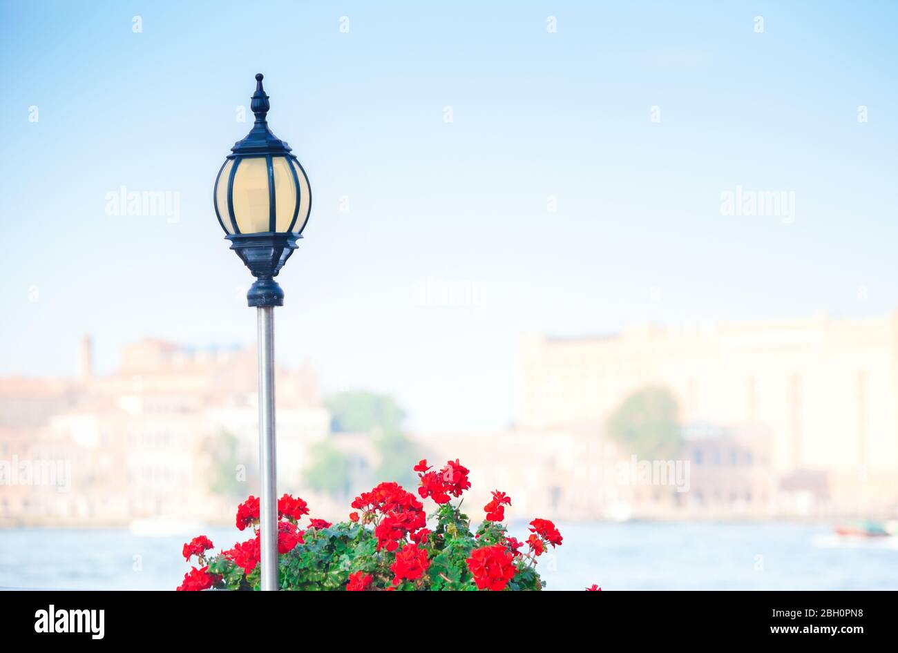 Softly lit lamp post and red geraniums in Venice, Italy in early ...