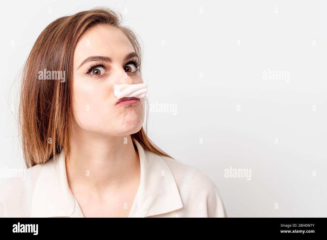 Young woman making mustache with sweet candy marshmallow on white ...