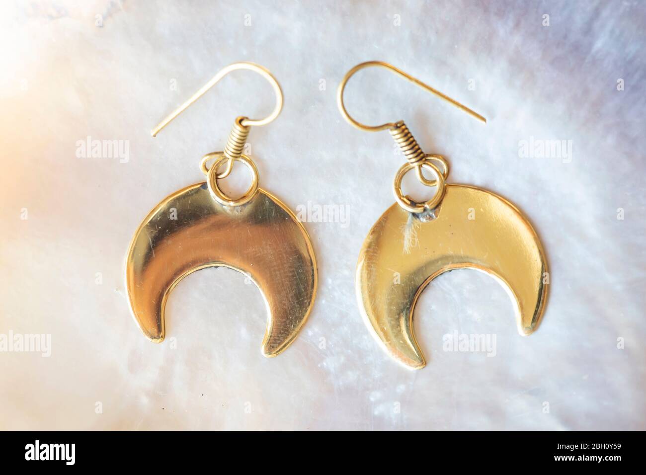 Brass elegant earrings in the shape of the moon on the white shell ...