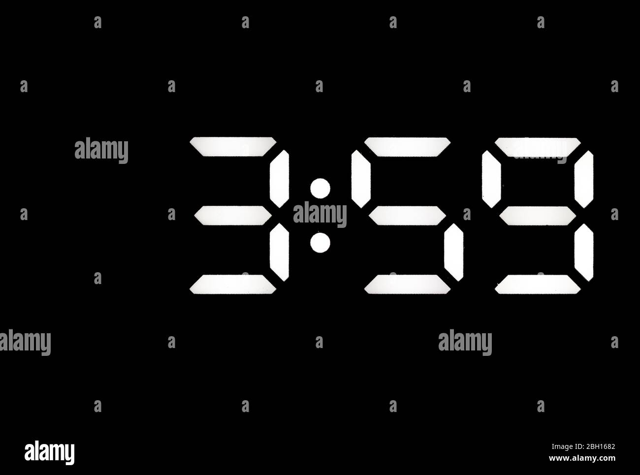 Real white led digital clock on a black background showing time 3:59 ...