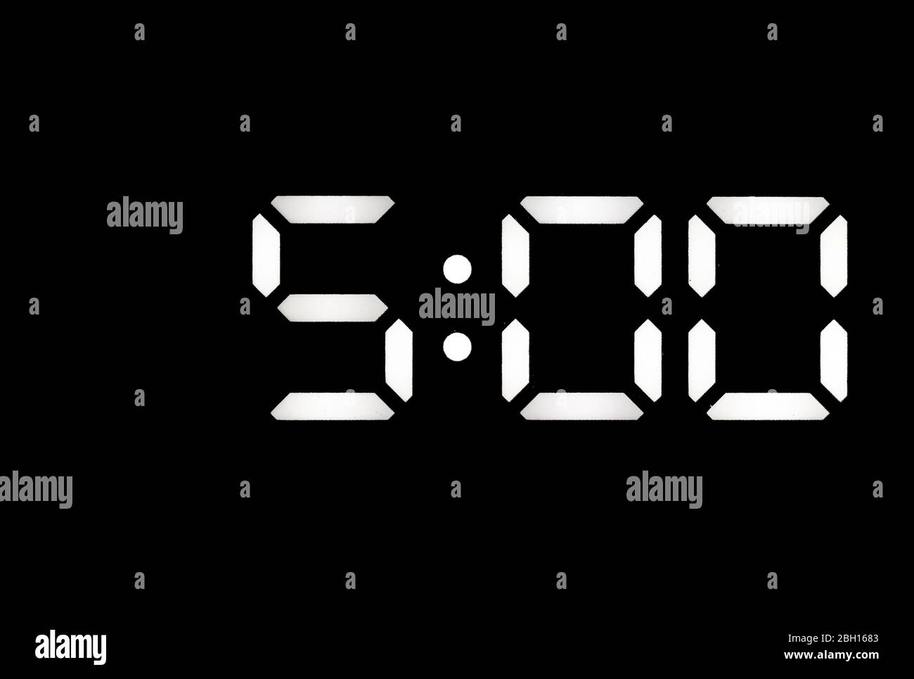 Real white led digital clock on a black background showing time 5:00 ...