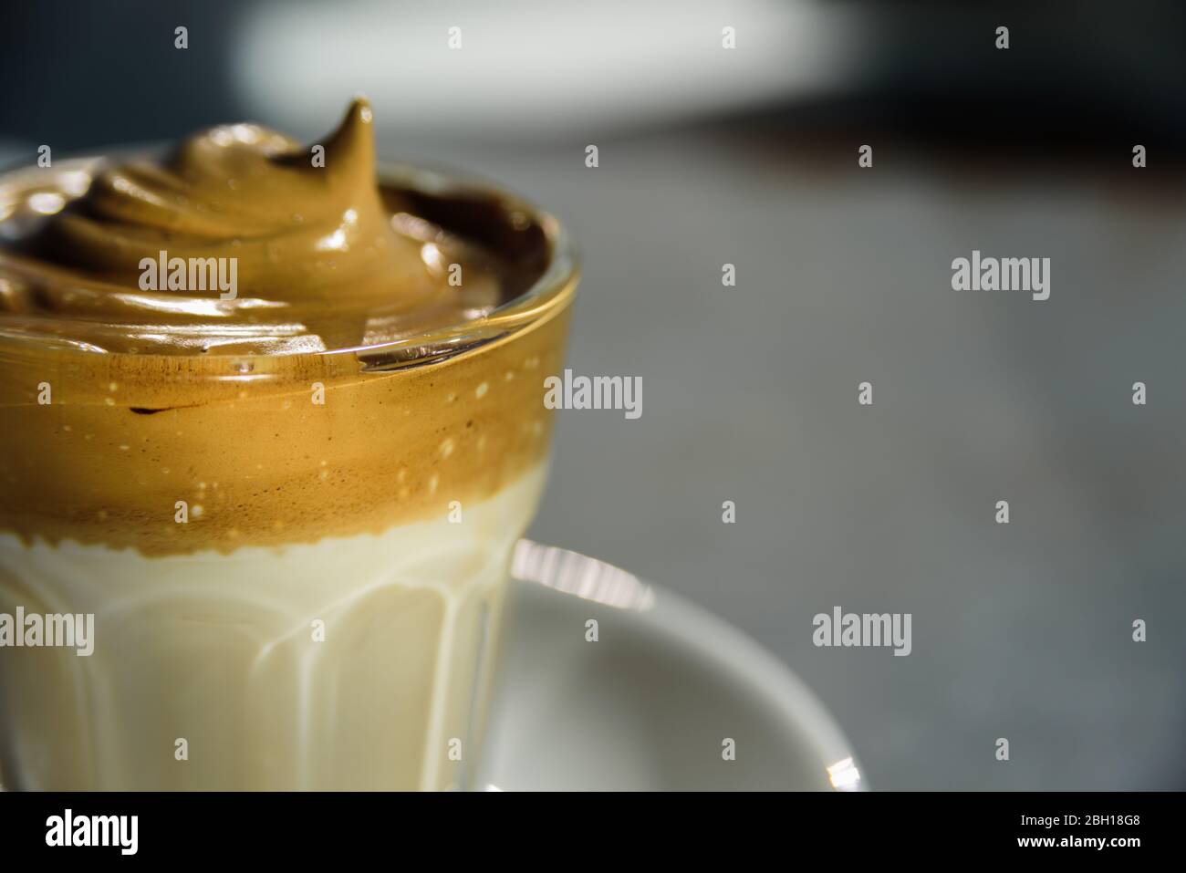 Dalgona instant coffee whipped drink in glass. Hard sun light, concrete ...