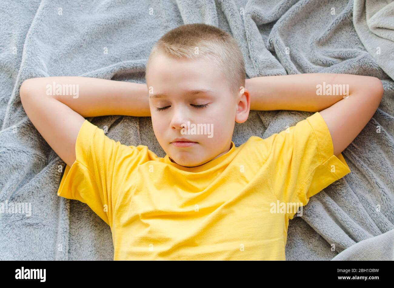 Blond boy sleeps at home. Child in yellow T-shirt resting lying on soft ...