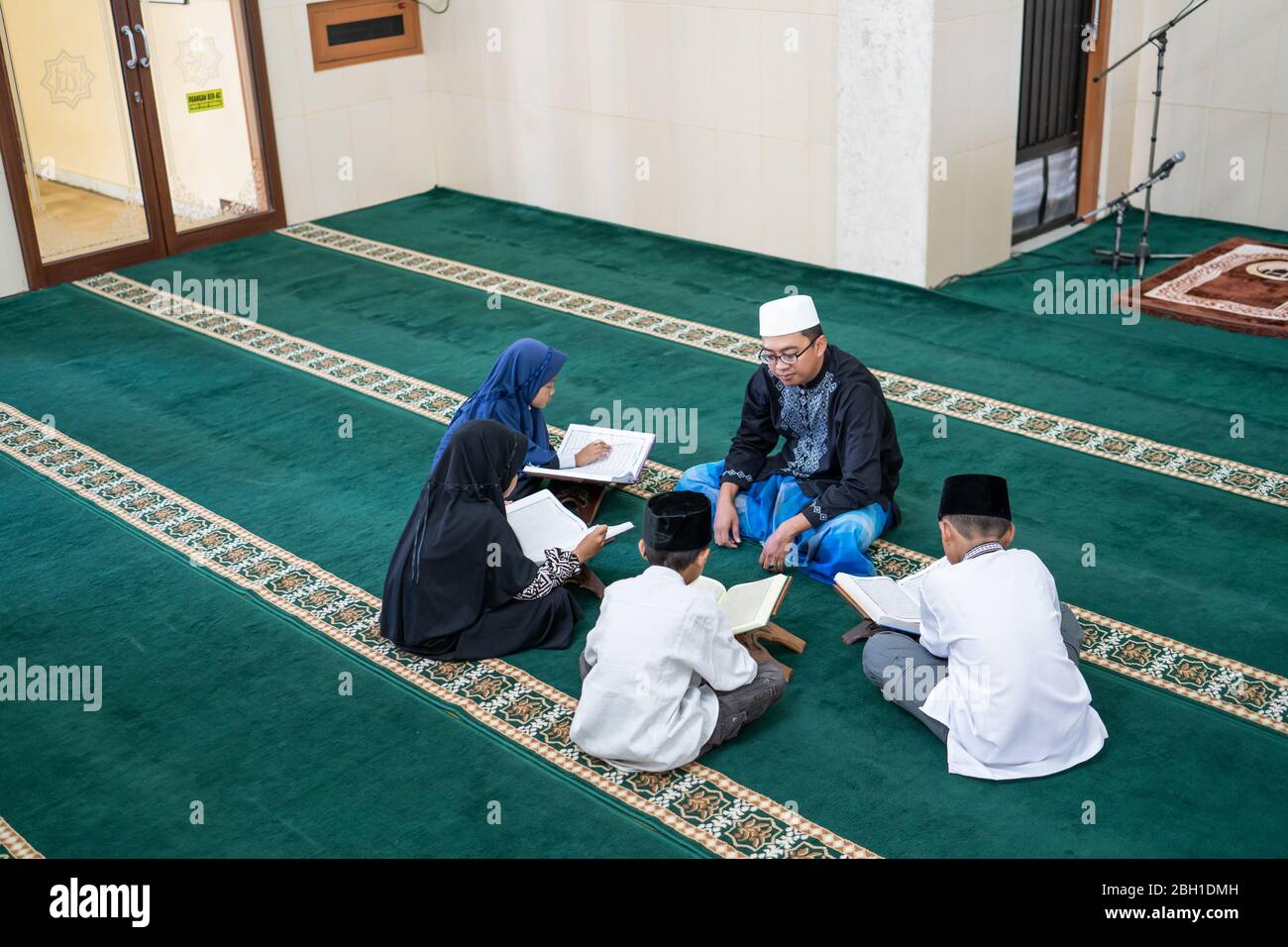 teacher is teaching muslim kid how to read holy quran in the mosque ...