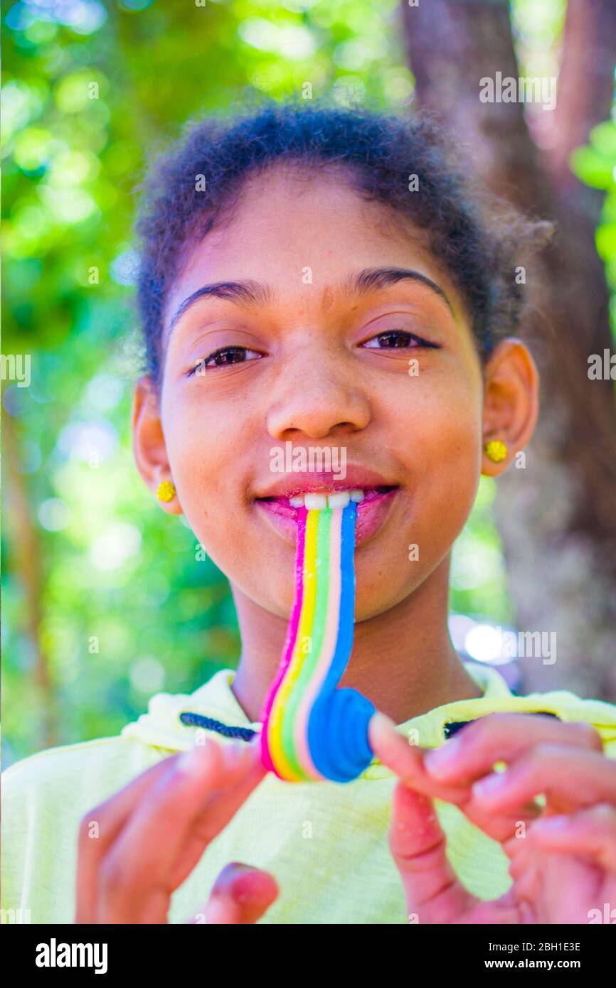 happy little girl smiles as she eats a soft licorice of all colors ...