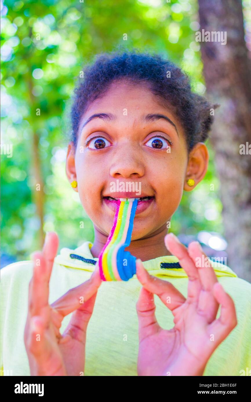 happy little girl smiles as she eats a soft licorice of all colors ...