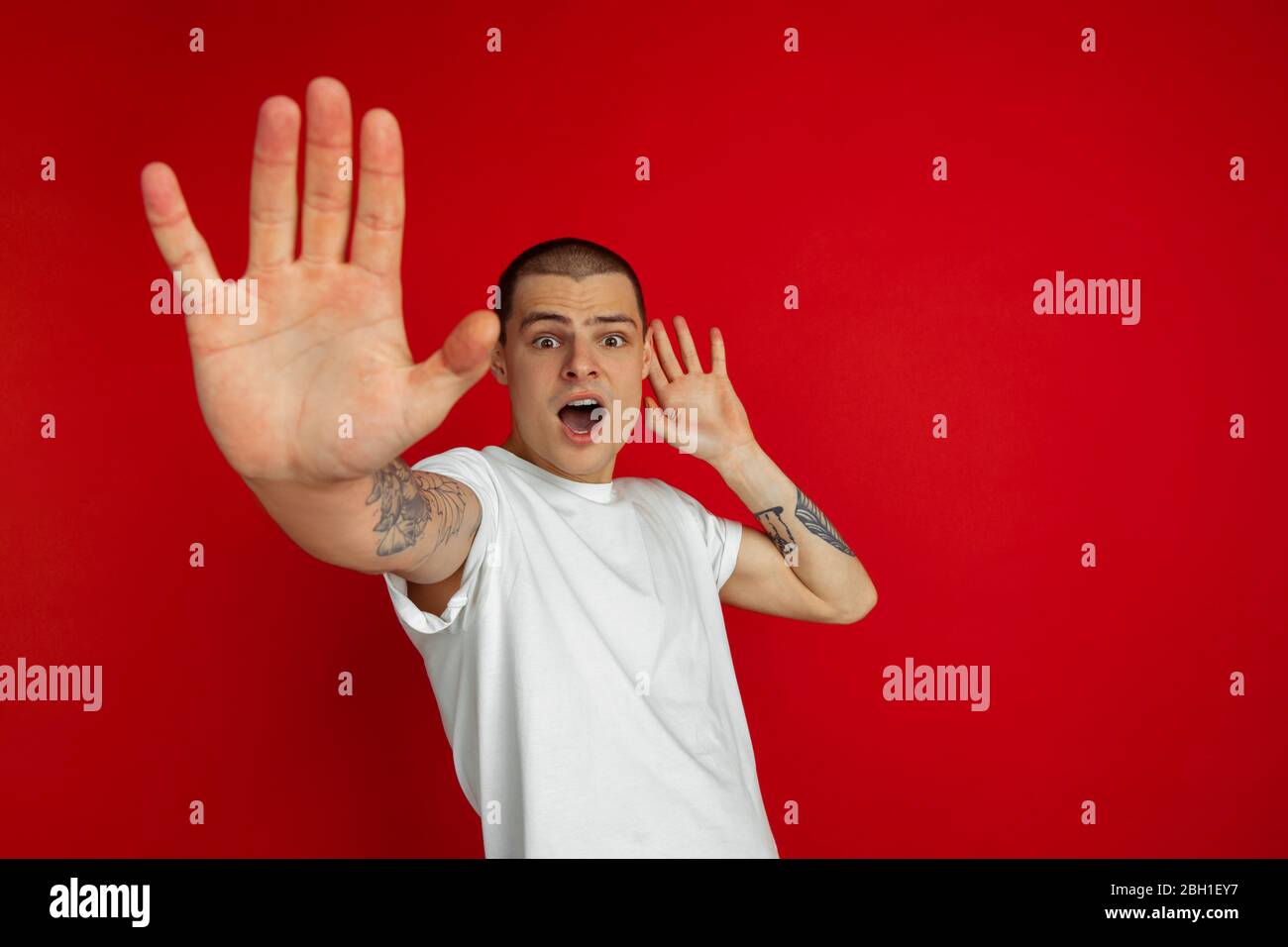 Shocked showing stop gesture. Caucasian young man's portrait isolated ...