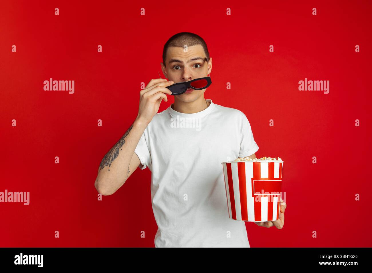 Crazy shocked, numb. Caucasian young man's portrait on red studio ...