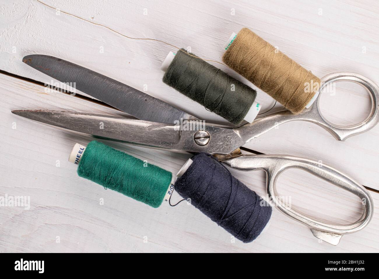 Sewing scissors with thread spools on white wood Stock Photo - Alamy