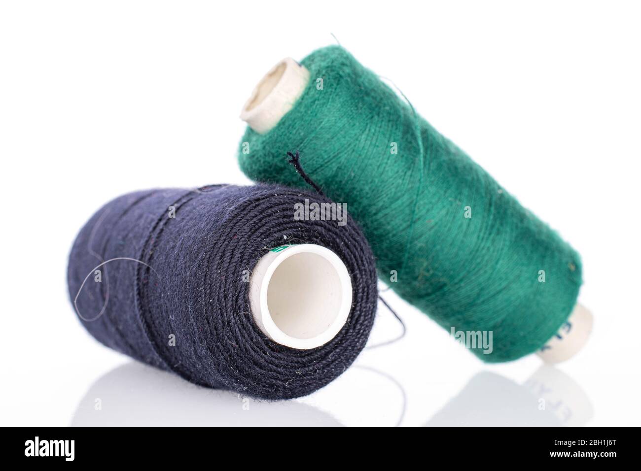 Group of two whole green and dark blue thread spools isolated on white ...