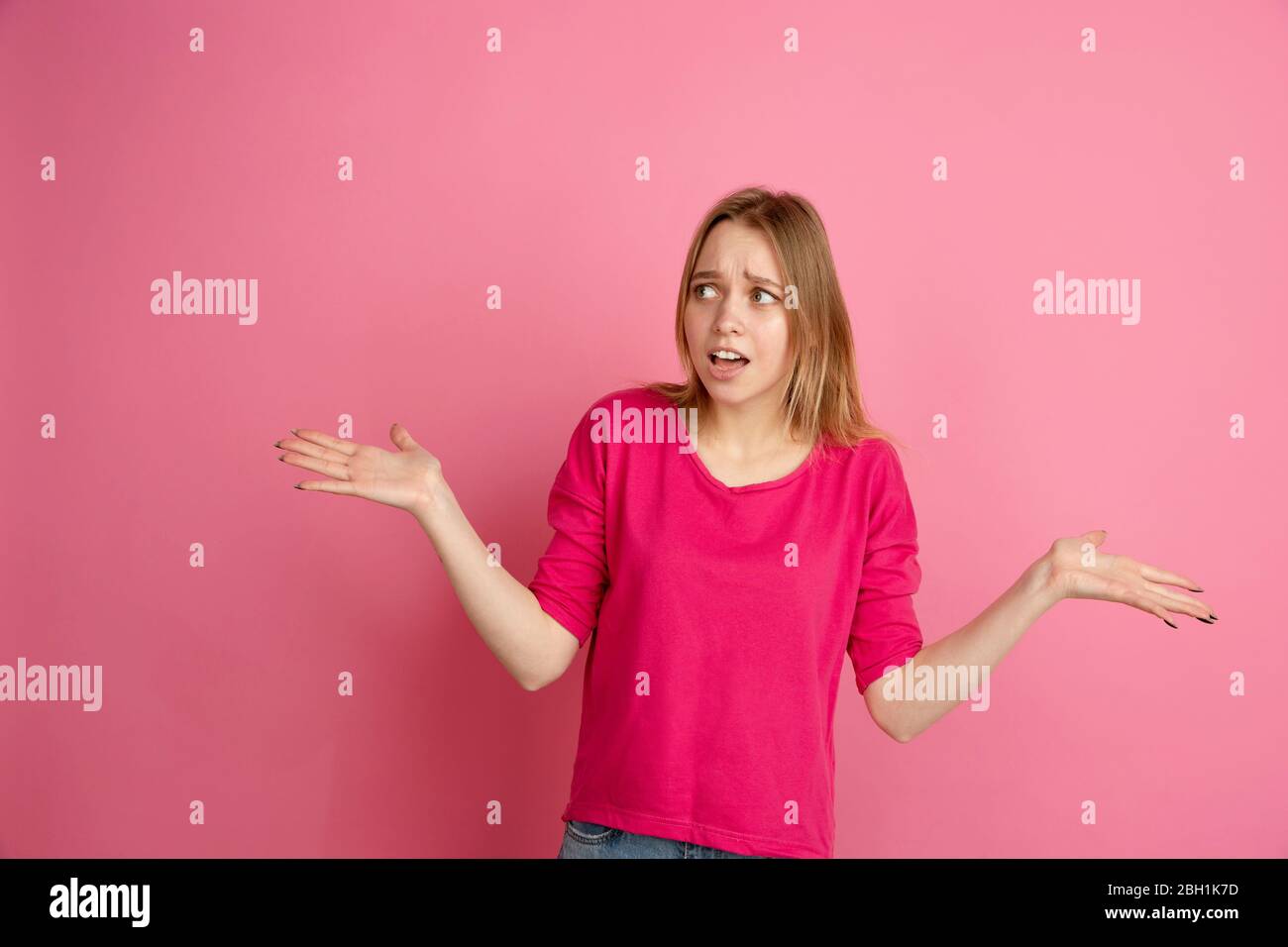 Shocked, uncertain. Caucasian young woman's portrait isolated on pink ...