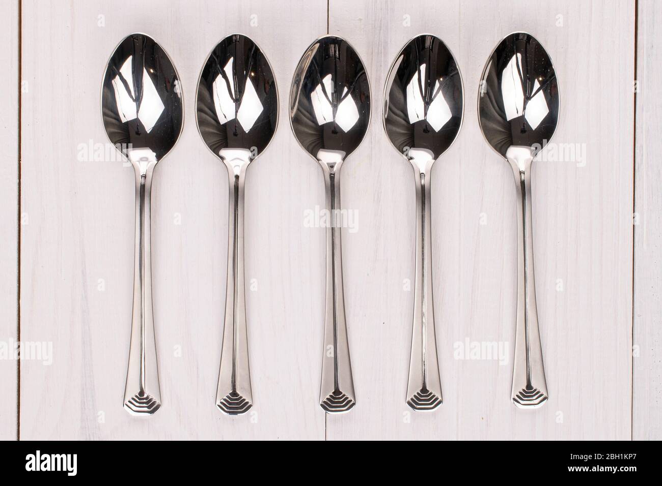 Group of five whole dessert spoons on white wood Stock Photo - Alamy