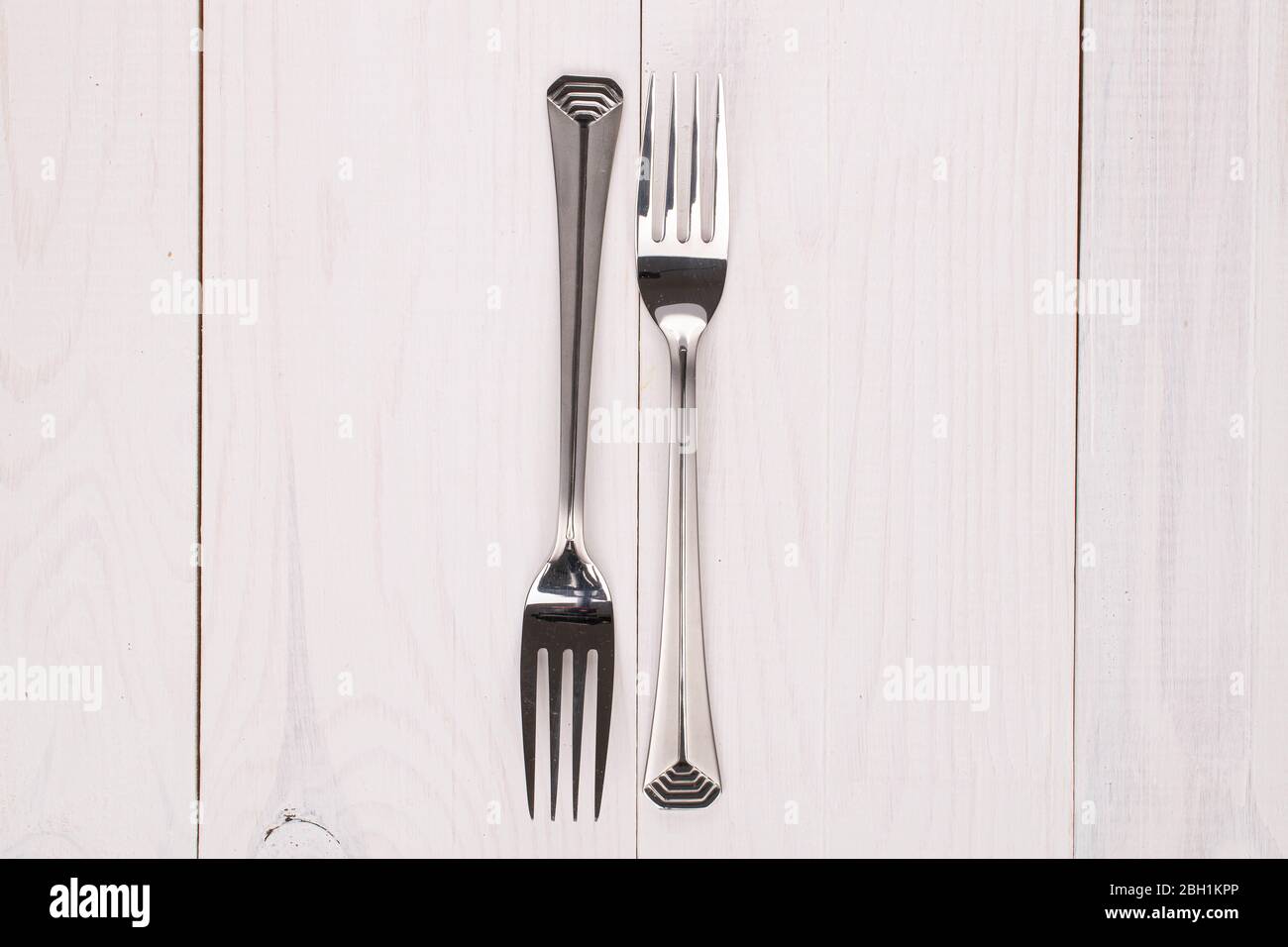 Group of two whole steel fork on white wood Stock Photo - Alamy