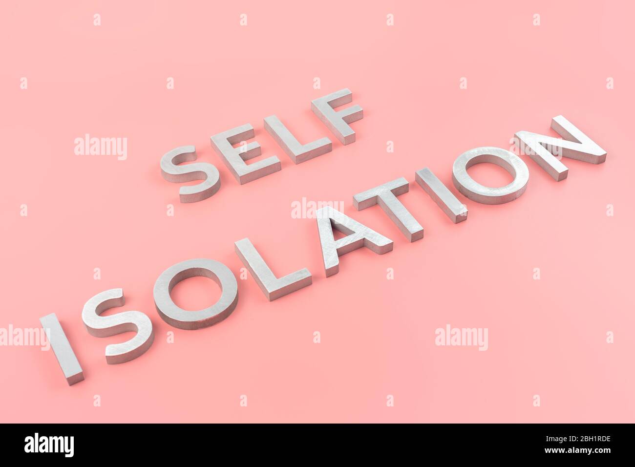 the words self isolation laid with silver metal letters on pink ...