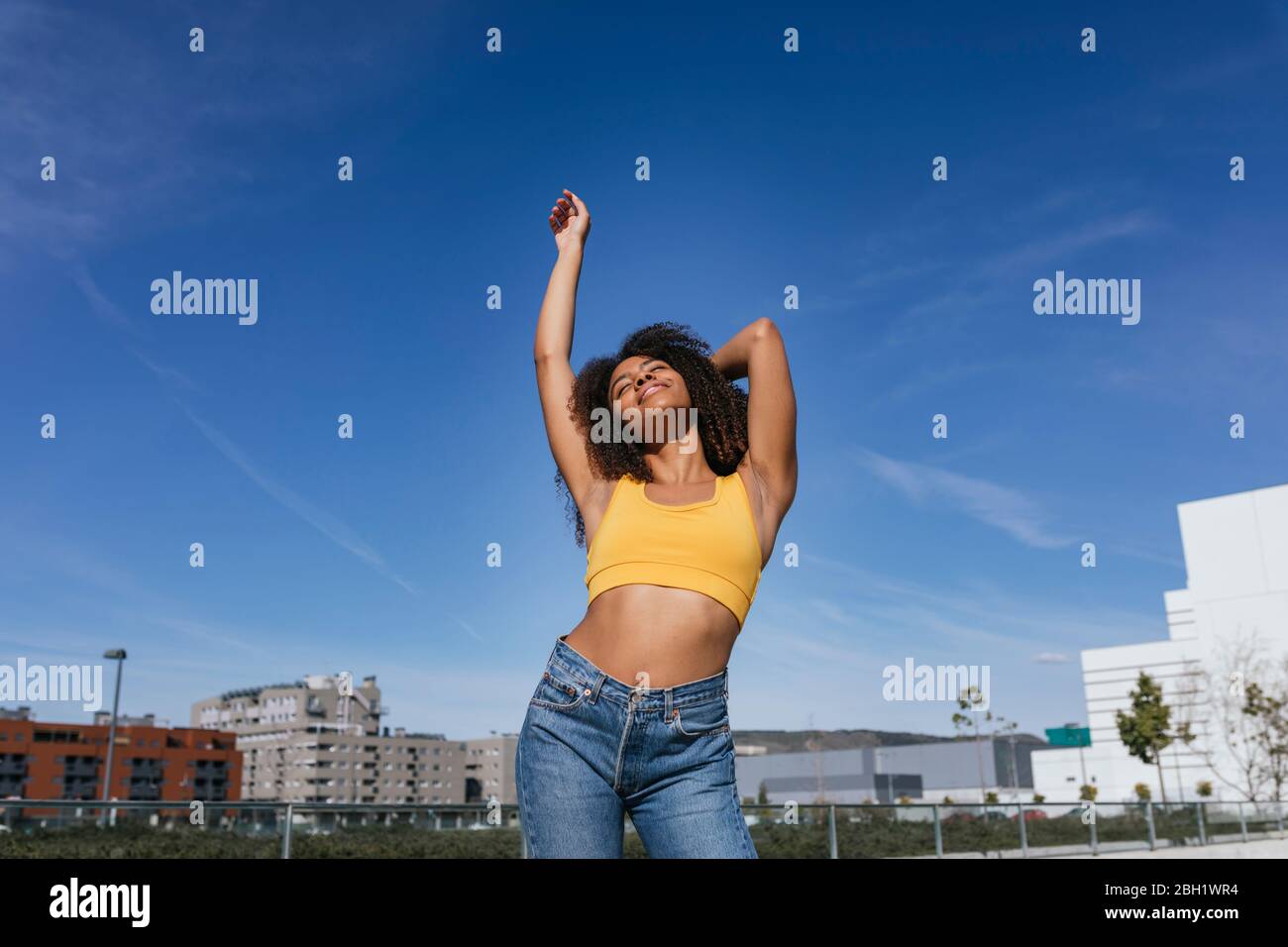Smiling young woman dancing with eyes closed Stock Photo - Alamy