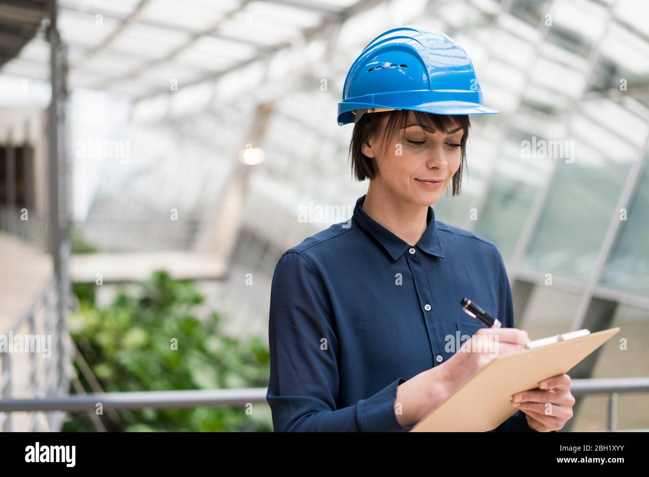 Female architect wearing blue hard hat, portrait Stock Photo - Alamy