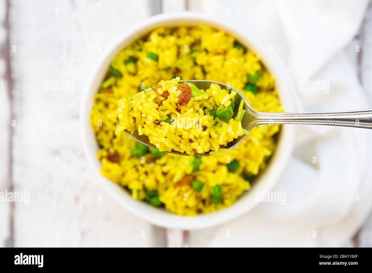 Spoon of pilau rice with green peas, raisins and turmeric Stock Photo ...