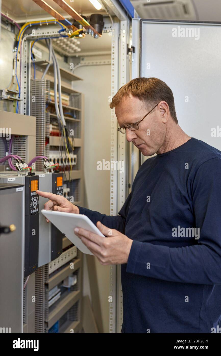 Electrician with tablet adjusting circuitry at junction box Stock Photo - Alamy