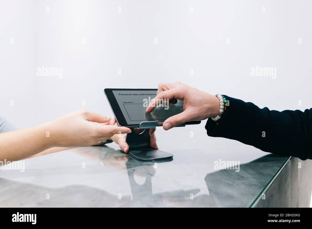 Close-up of man at reception desk of a medical practice using digital ...