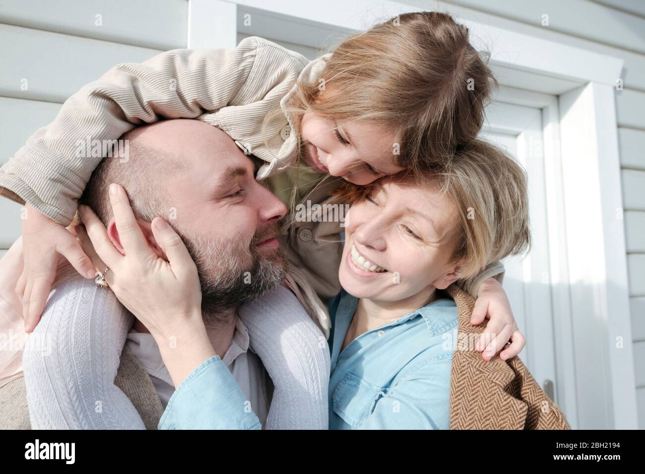 Happy family hugging in front of their house Stock Photo - Alamy