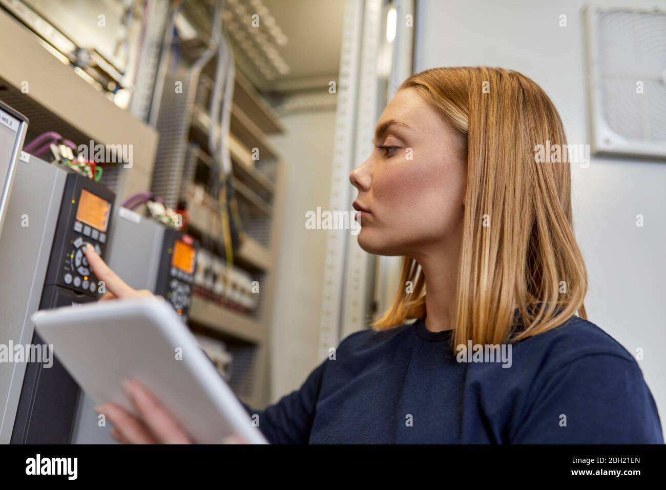 Female electrician with tablet adjusting circuitry at junction box ...