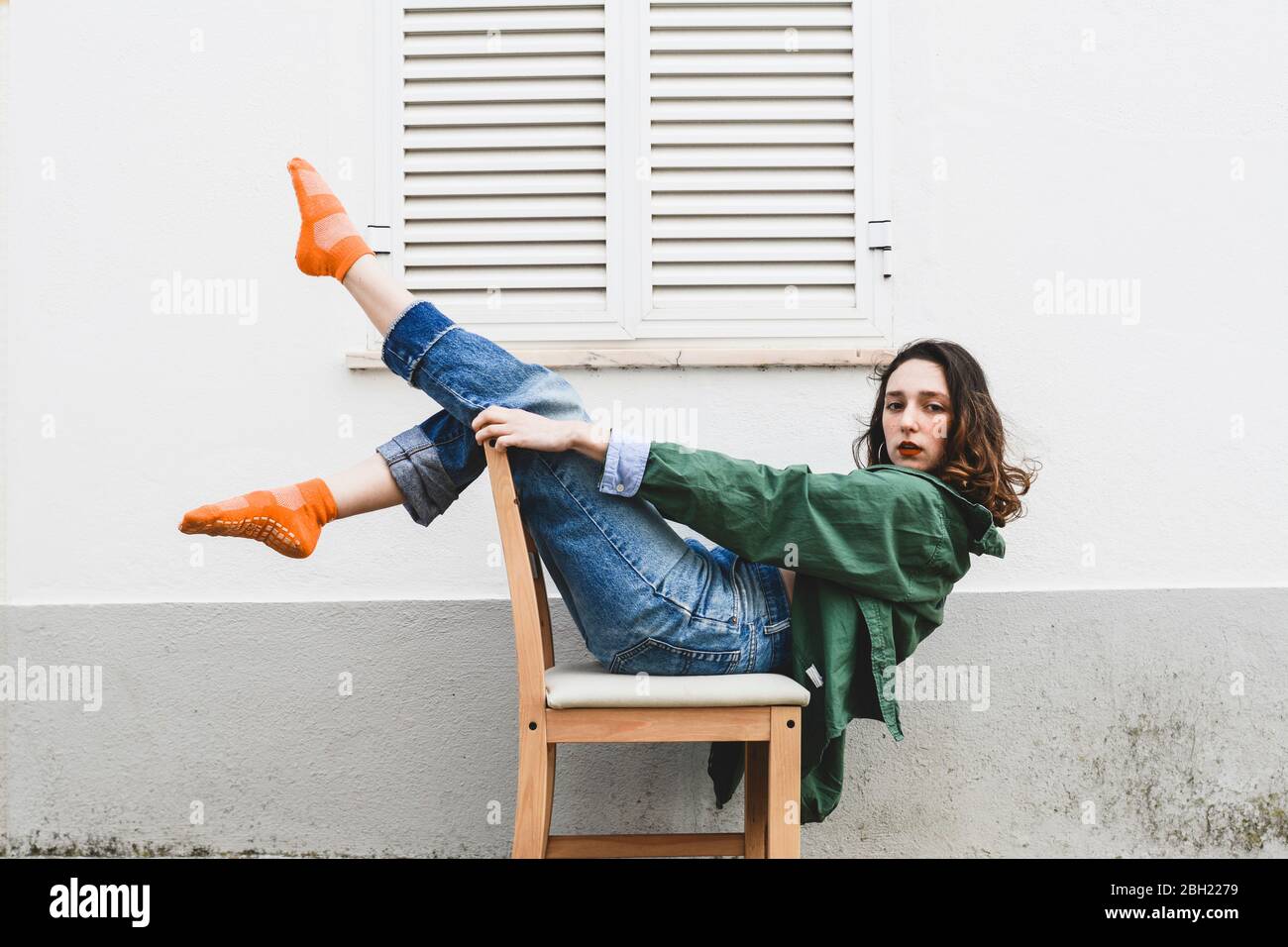 Portrait of young woman balancing on a chair outdoors Stock Photo - Alamy