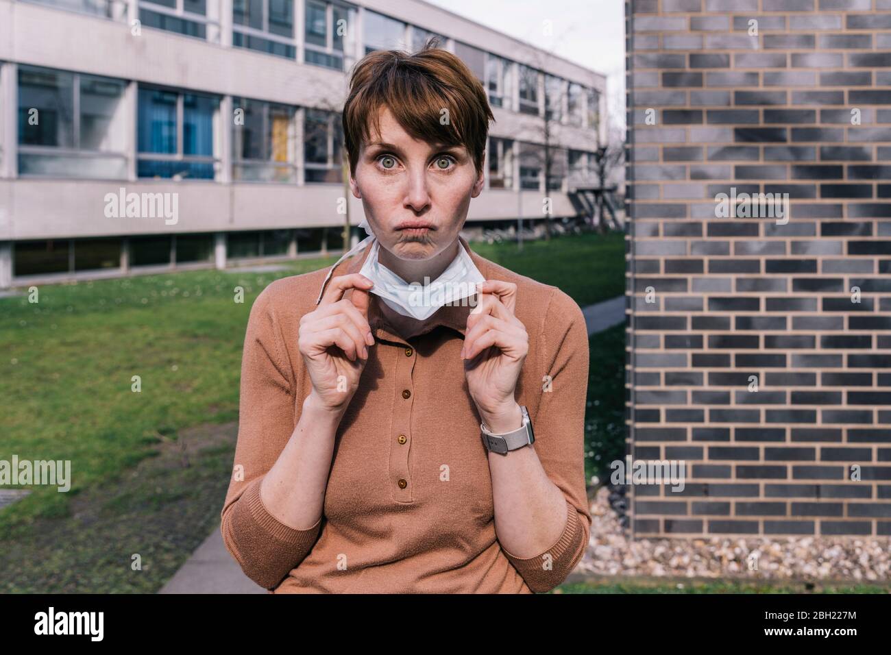 Portrait of woman taking off mask and pulling faces Stock Photo - Alamy