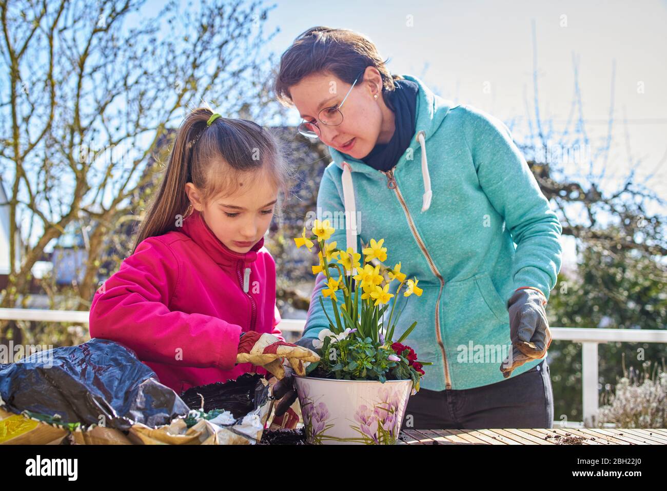 Mother and daughter planting flowers together on balcony Stock Photo ...