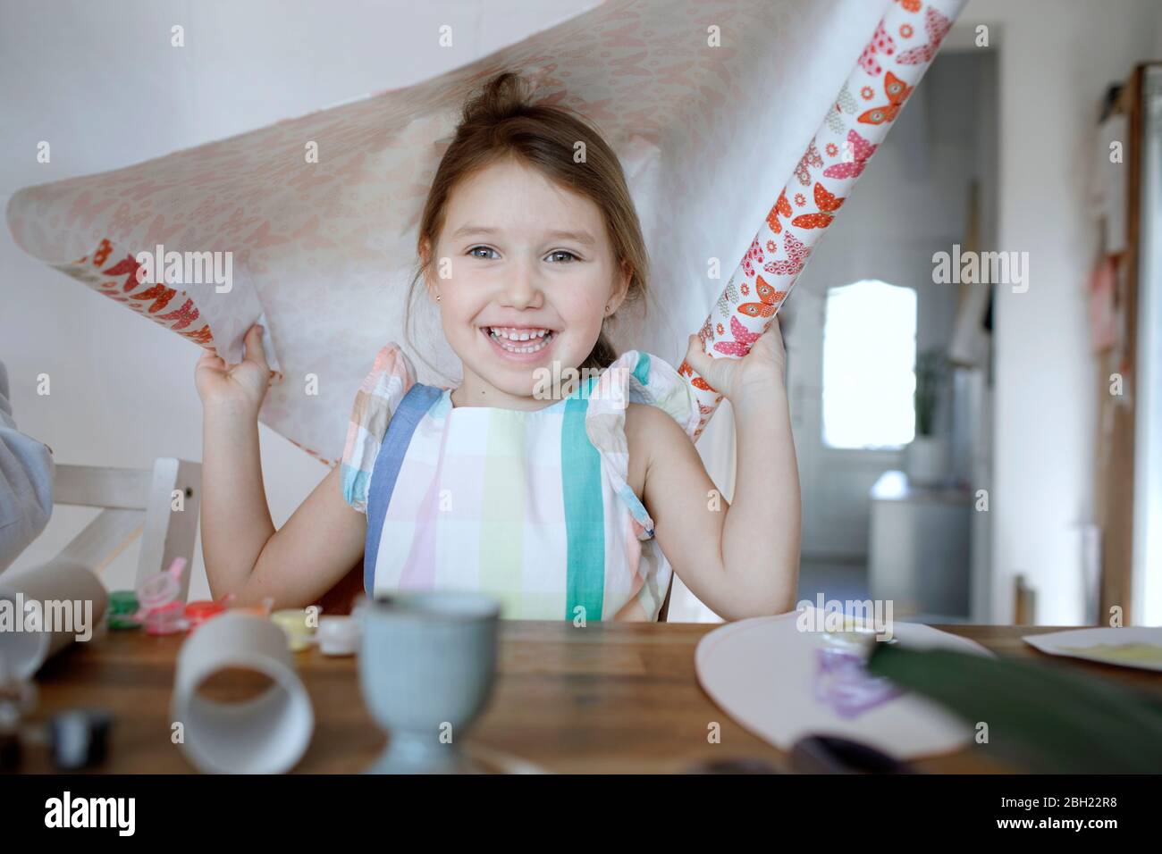 Portrait of happy little girl tinkering with paper Stock Photo - Alamy