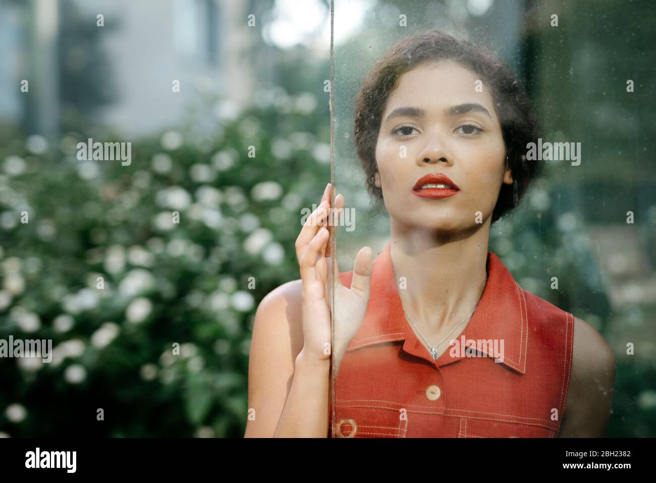 Portrait of young woman behind glass pane Stock Photo - Alamy