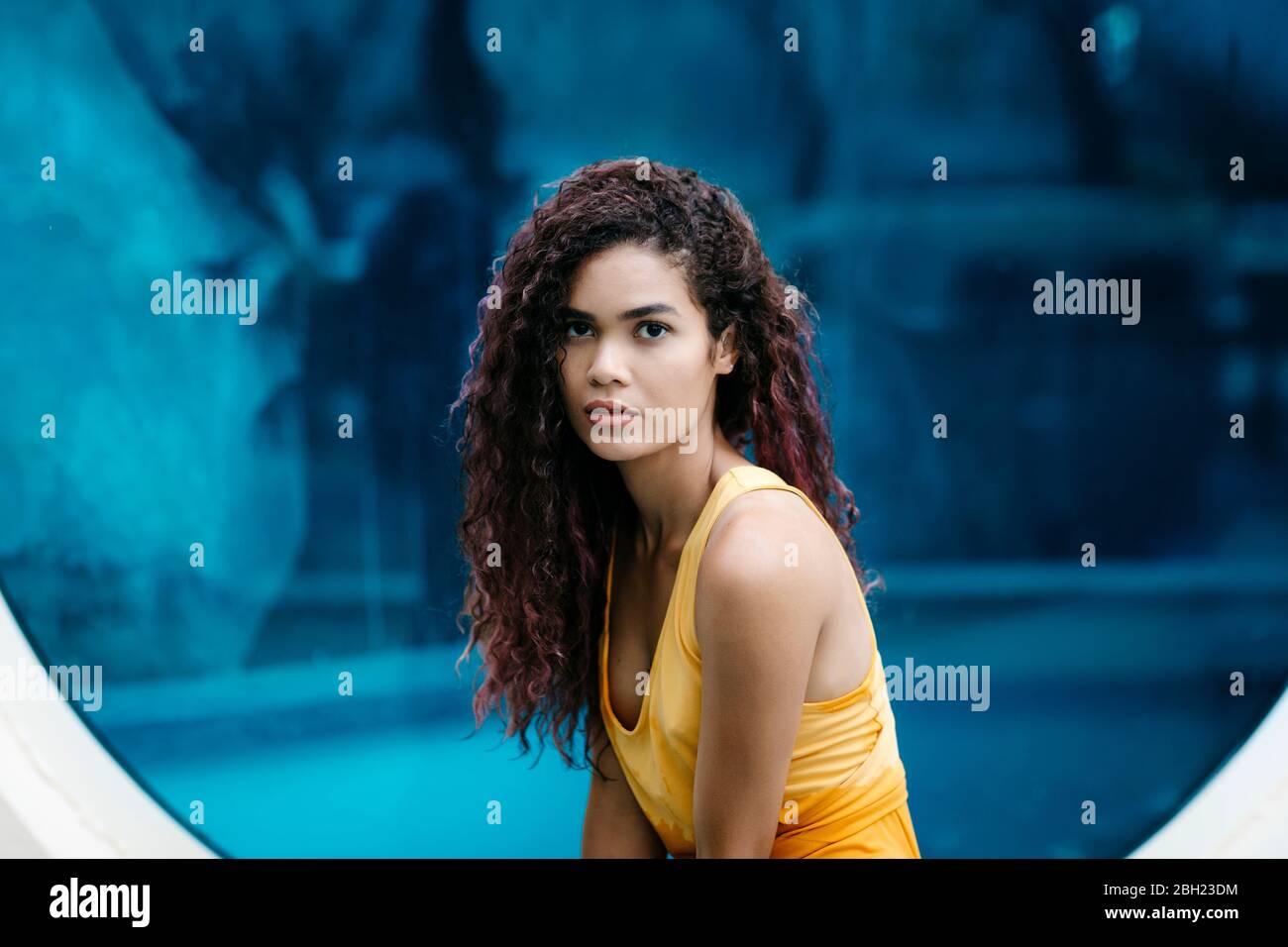Portrait of young woman with ringlets in front of blue background Stock ...