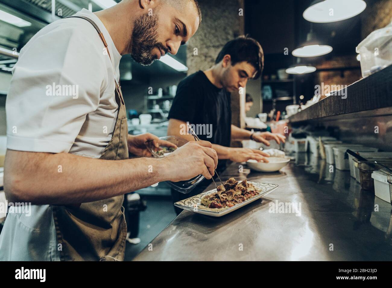 chefs in restaurant arranging food on plates for serving Stock Photo ...